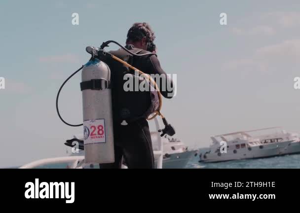 The scuba diver jumps into the ocean. In slow motion, the scuba diver ...