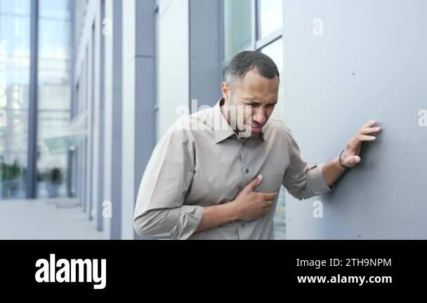 A man experiences a sharp pain in his chest standing on the street near ...