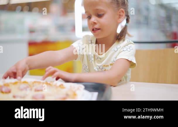 Child eat pizza sitting on the table at food court in supermarket ...