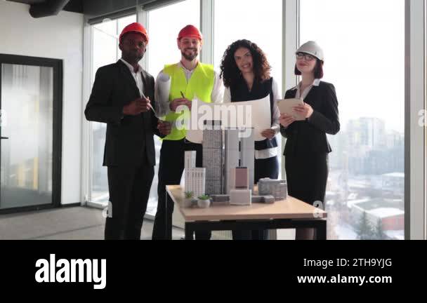 Group of four colleagues standing near building complex prototype ...