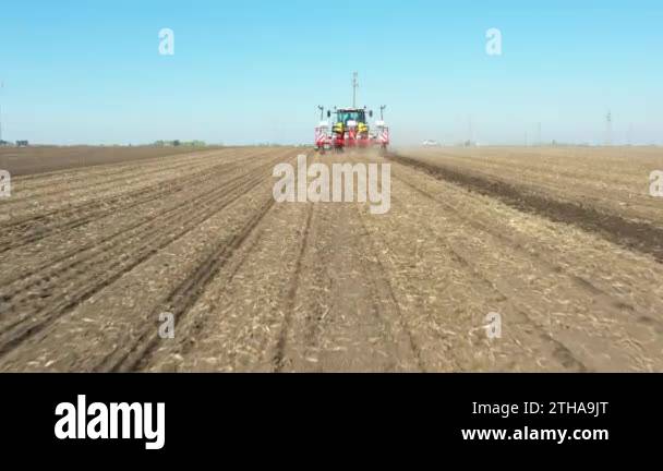 Above from the back view, fly low from behind, tractor is pulling ...