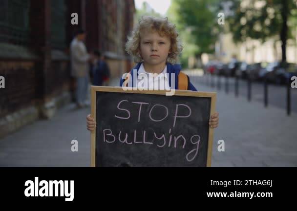 Little boy standing near school loooking at camera and holding ...