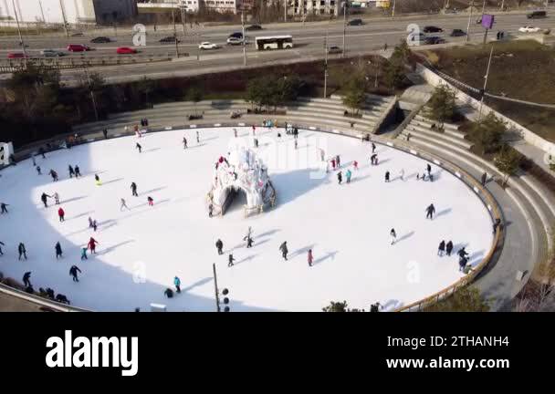 City ice skating rink in open air and road bridge in city. Aerial drone ...