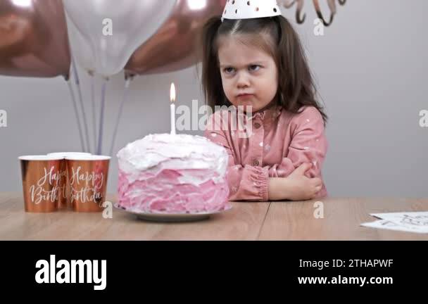 An angry little girl is sitting at the festive table next to the ...