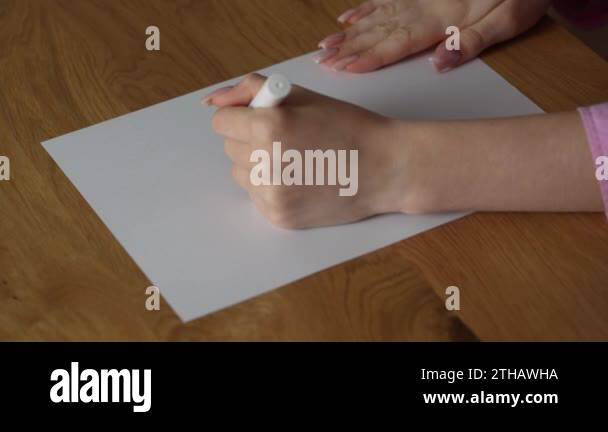 Girl on a white sheet draws a question mark with a black marker ...