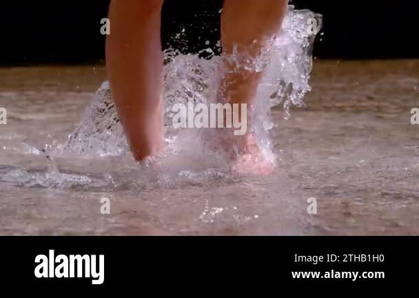 Young barefoot woman walking in shallow mountain river. Drops of water ...