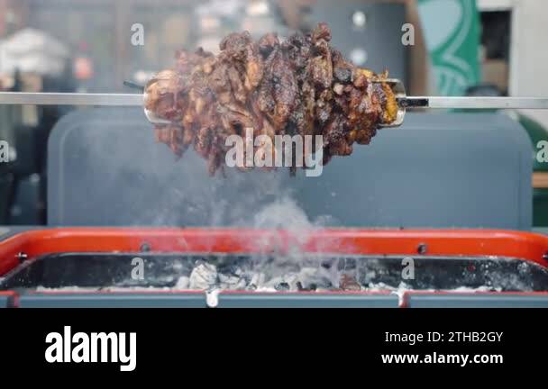 Variety of meat slices on bbq skewer rotating and roasting on barbecue ...