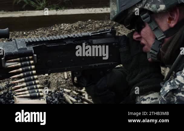 Close-up of a soldier's firing a belt-fed machine gun. The chain of ...