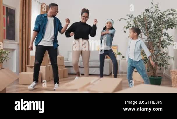 A happy family dances in the middle of the living room, young parents ...