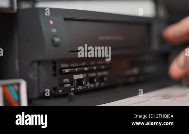 Eject VHS tape cassette from VCR player. Male hand pulls out VHS from a ...