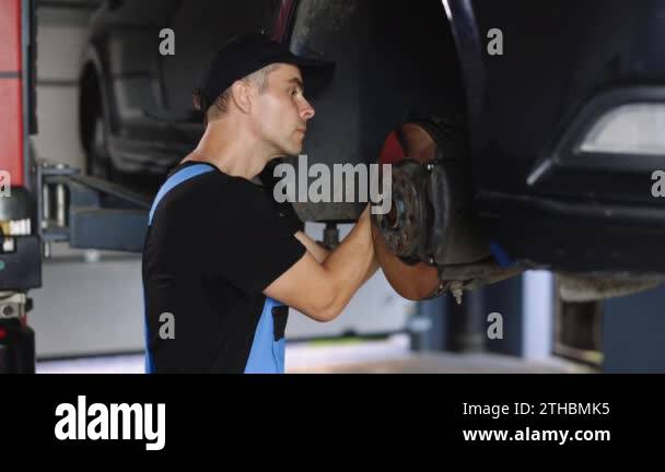 Car mechanic replacing car wheel brake shoes of lifted automobile at ...