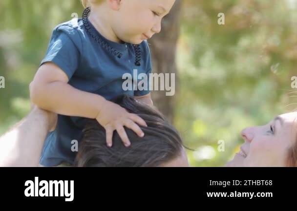 Little boy sitting on the neck of his father and touching his mother ...