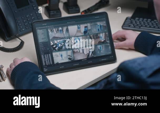 Security officer controls CCTV cameras in coworking office, uses ...