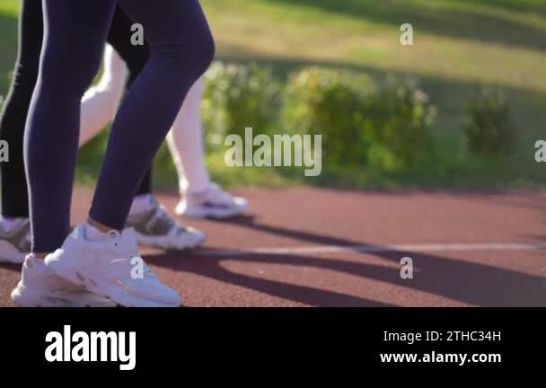 Side view legs of sportswomen walking on red sports track as live ...