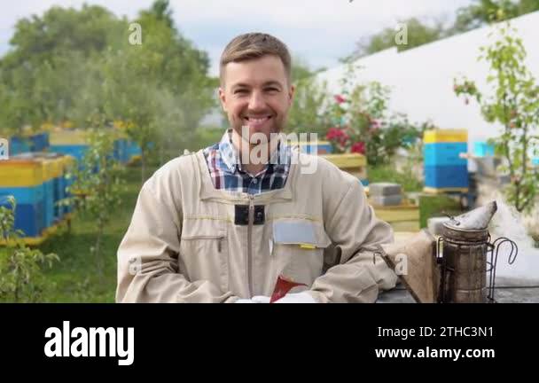 Beekeeper at Work. Bee keeper lifting shelf out of hive. The beekeeper ...