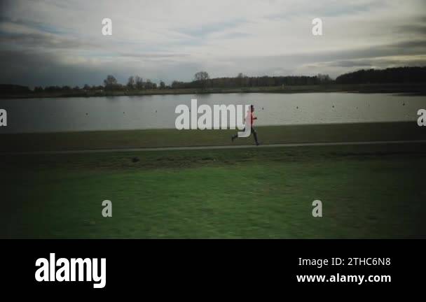 Man running along lake in park in Germany. Athletic young person runs ...