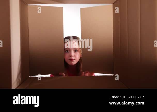 Little girl, child unpacking, opening cardboard box with sad crying ...