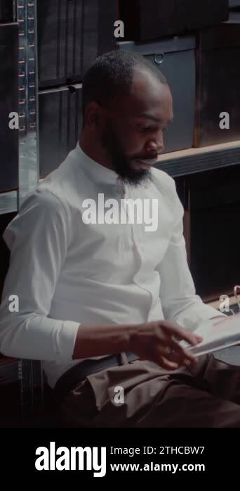 Vertical video: Police officer sitting on archive room floor with files ...