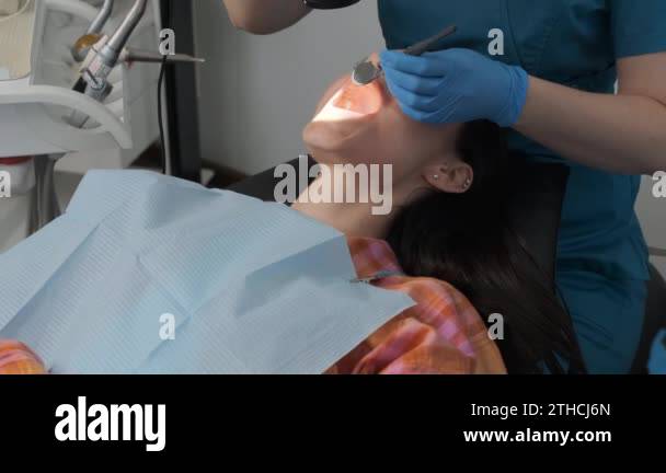 Dentist examining woman teeth and mouth with dental mirror and ...
