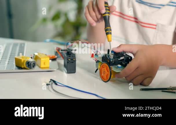 Little child tighten the nut with a screwdriver to assemble car toy ...