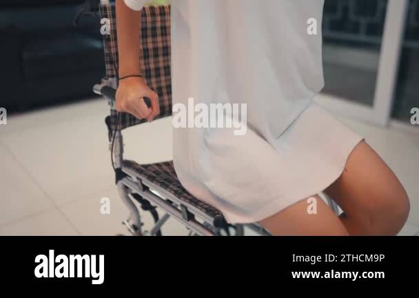 A paralyzed woman is trying to stand up from her wheelchair with an ...