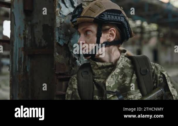 Caucasian woman in military uniform standing on damaged manufacture ...