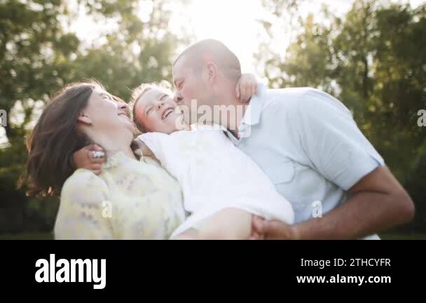 Happy family, dad mom and daughter hugging in the park at summer sunset ...