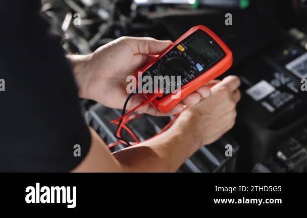 Man using multimeter to measure the voltage of the batteries. Mechanic ...