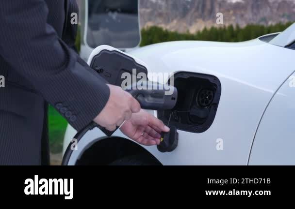 Progressive businessman recharge electric vehicle installing power ...