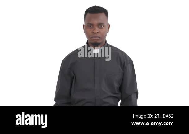 Side view portrait of African young priest pointing finger to side and ...