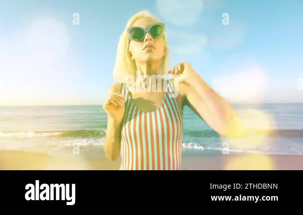 A beautiful woman dancing at the beach in a bikini with mirror balls ...