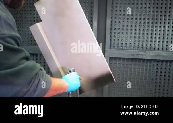 Man applying black anti-corrosion powder coating to metal sheet using a ...