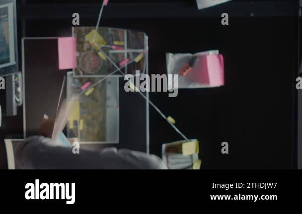 Vertical video: Professional police officer hanging clues on wall map ...