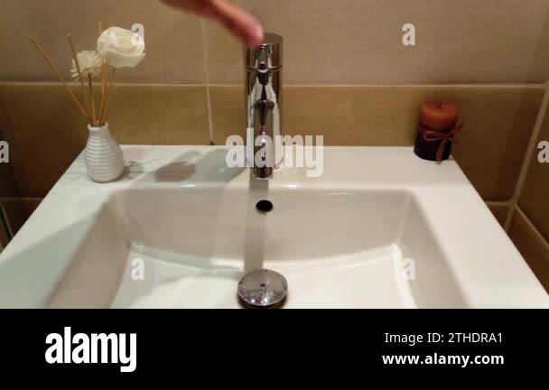 Running water from luxury bathroom white sink in hotel room. Stainless ...