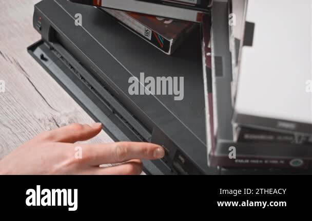 Eject VHS tape cassette from VCR player. Male hand pulls out VHS from a ...