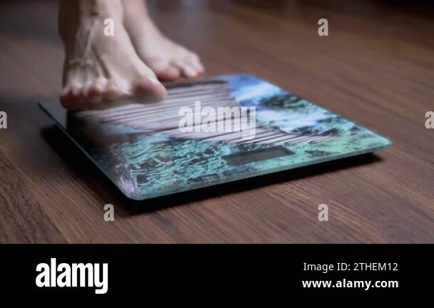 Male on the Scales Measures the Weight. Close up. A man barefoot steps ...