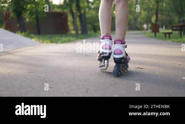 Close-up of the legs of a girl riding rollerblades. Rear view of a ...