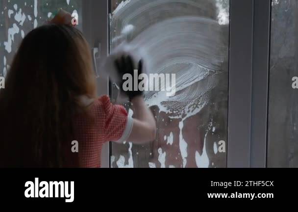 A woman wipes the window of her house from the remains of water, dirt ...