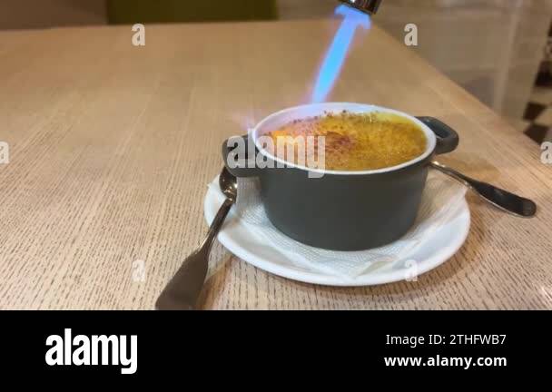waiter using gas burner for preparing a cream caramel creme brule set ...