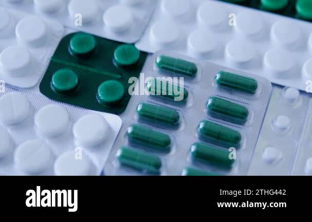 Different white and green tablets lying on rotating table, random ...