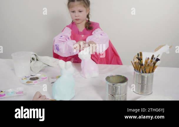 Little girl painting paper mache figurine at homeschooling art class ...