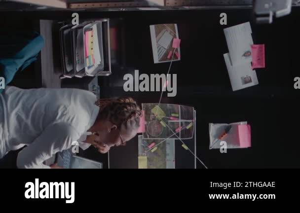 Vertical video: Law enforcement agent reading archive records at desk ...