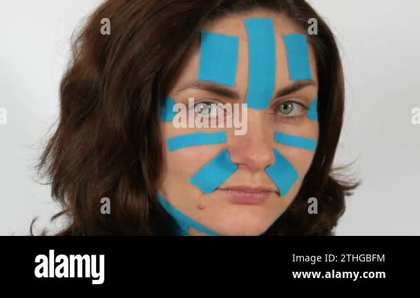 Young woman applied light blue kinesio strips taping face, forehead ...