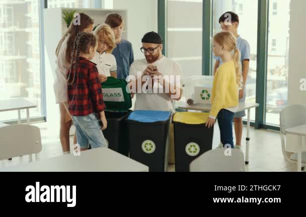 Male teacher shows to the pupils how and where sort rubbish correctly ...