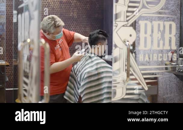 A side view of a happy guy getting haircut by hairdresser in a salon ...