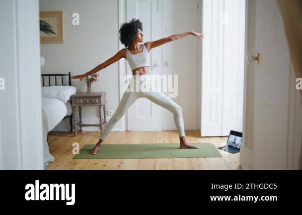 Flexible woman stretching body in cozy place. Curly hair athlete ...