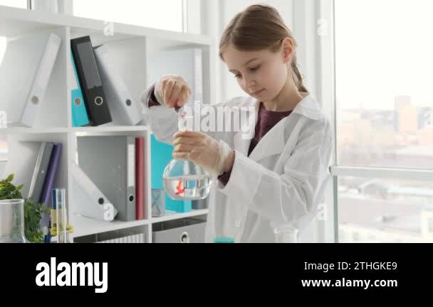 School girl put into bottle with water red liquid in chemistry class for chemical reaction ...