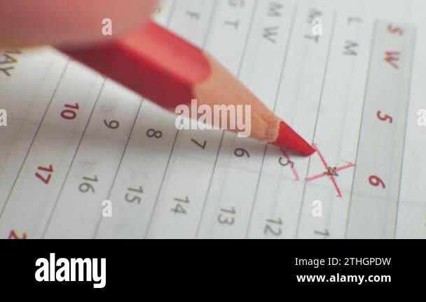 The month number calendar is cut out. Male hand write the day on a ...