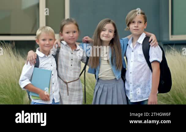 Four friends, elementary school students, stand in an embrace in the ...