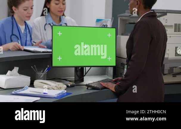 Diverse medical staff working with greenscreen on computer at hospital ...